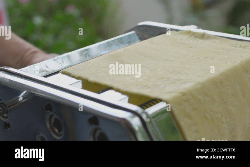 Stretching home made dough on a rolling machine. Preparation of thin ...