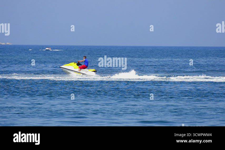 man on jet ski drive to lighthouse island. A man cruises the ocean on a ...
