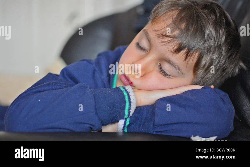 Sleepy boy on sofa shows shh hush expression sign for quiet atmosphere ...