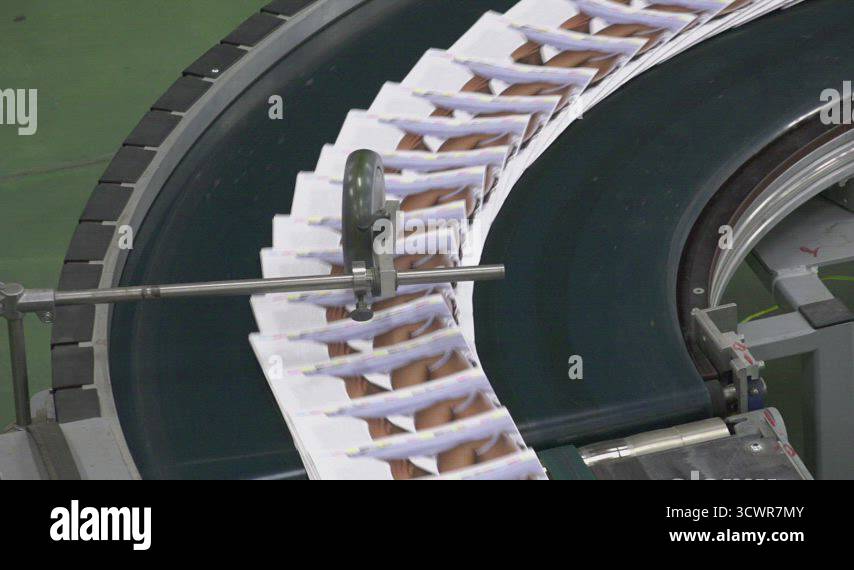 Newspapers flow along an assembly line in a newspaper print factory ...