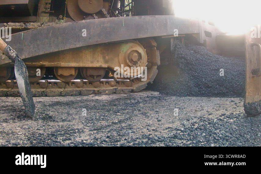 Clip of heavy equipment asphalt laying machine dropping blacktop tar ...