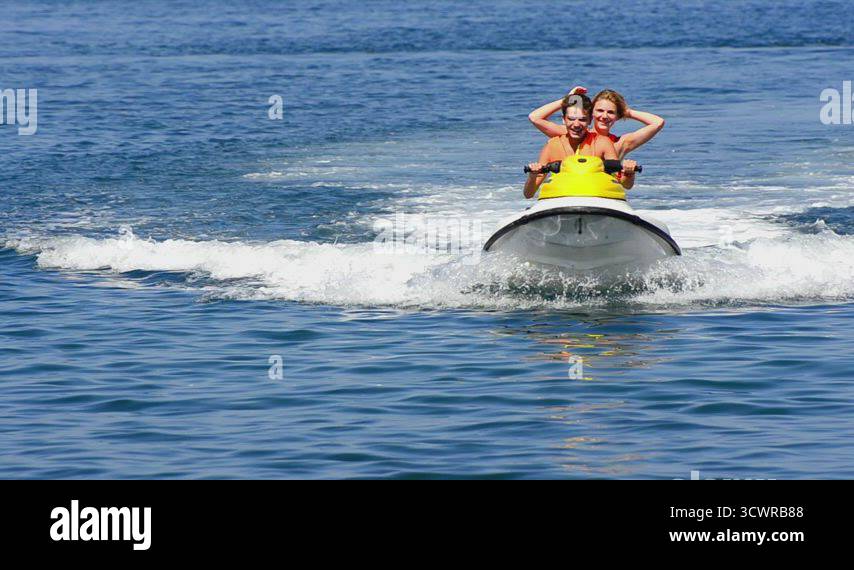 HAPPY COUPLE on JET SKI. Teen couple cruises the ocean on a jet ski ...