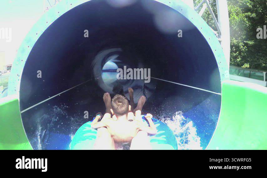 Family having joy, fun sliding down water slide tube in aqua park Stock ...