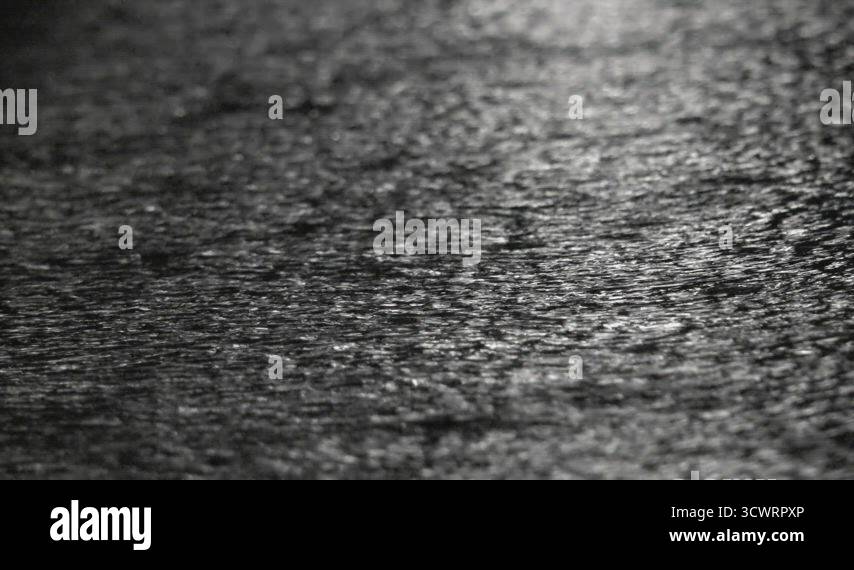 Closeup footage rain on water surface with reflection at dark night ...
