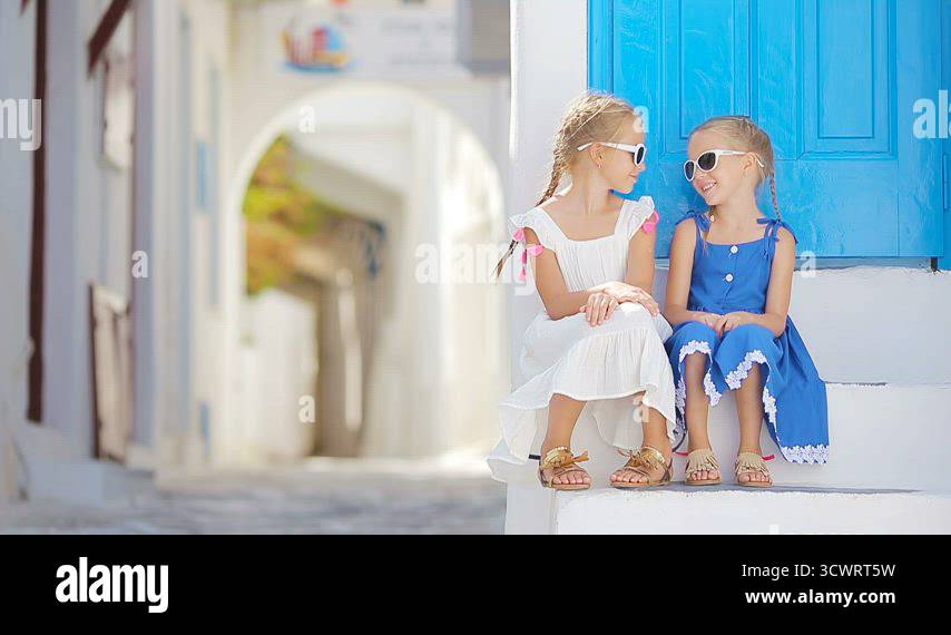 Two girls in blue dresses having fun outdoors. Kids at street of ...