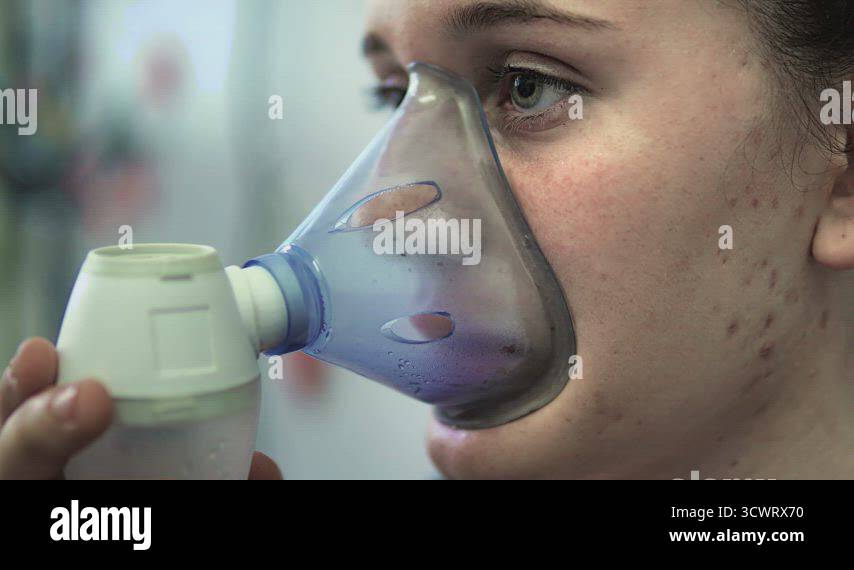 Sick girl with a sore throat makes inhalation with a mask on his face ...