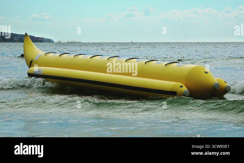 Colorful Banana boat anchored in shallow water move on sea waves Stock ...