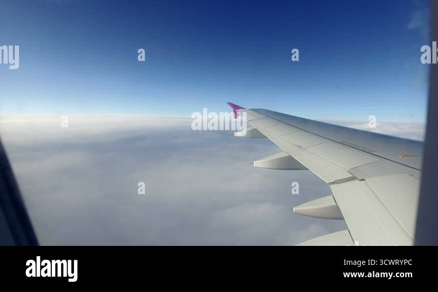 Passenger POV looking through the Window of plane flying over clouds ...