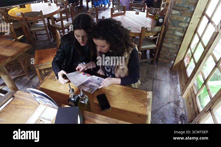 Two beautiful teens looking at restaurant menu choosing a meal Stock ...