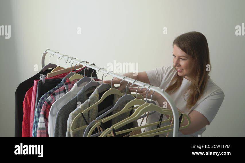 Young woman choosing clothes on a rack searching what to wear. Store or ...