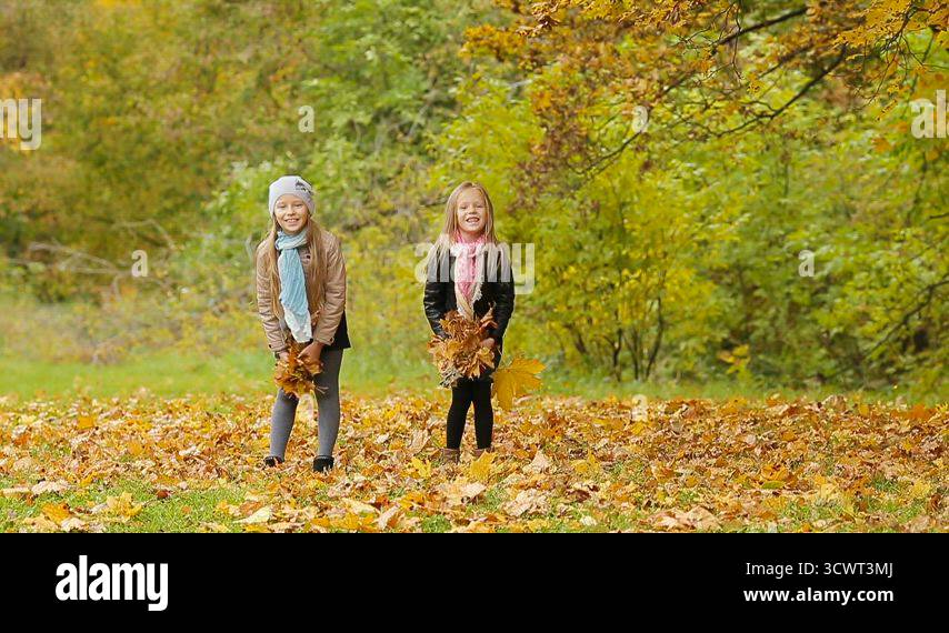 Little adorable girls having fun with leaves at warm day in autumn park outdoors Stock Video ...