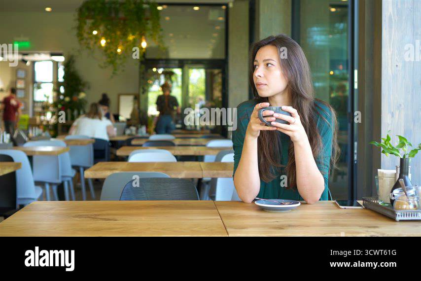 Young charming woman calling with cell telephone while sitting alone in ...
