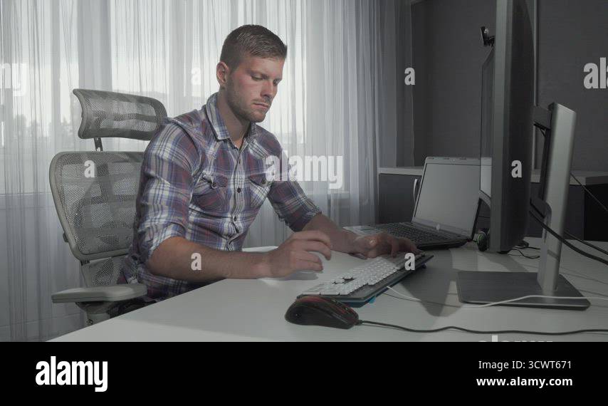 Handsome IT office worker using two computers working on a project ...