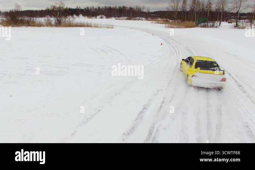 Car drives by icy track on snow covered lake at winter. Aerial view ...