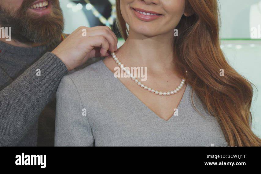 Cropped shot of a man adjusting pearl necklace on the neck of his wife ...