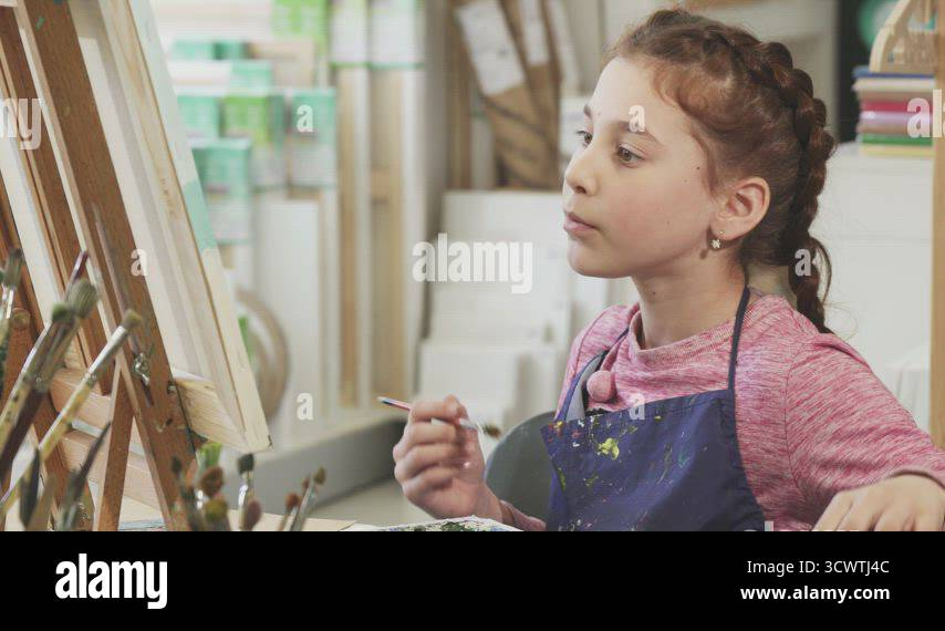 Cute little girl showing thumbs up while painting a picture at the art ...