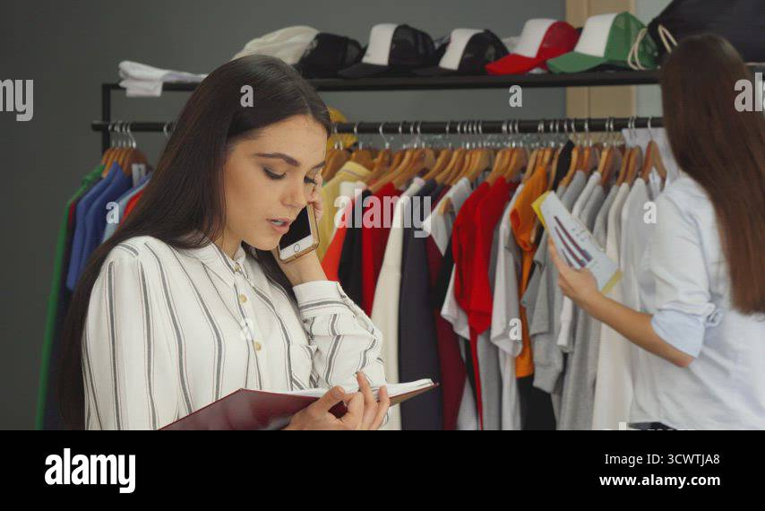 Beautiful female shop assistant talking on the phone, working at the ...