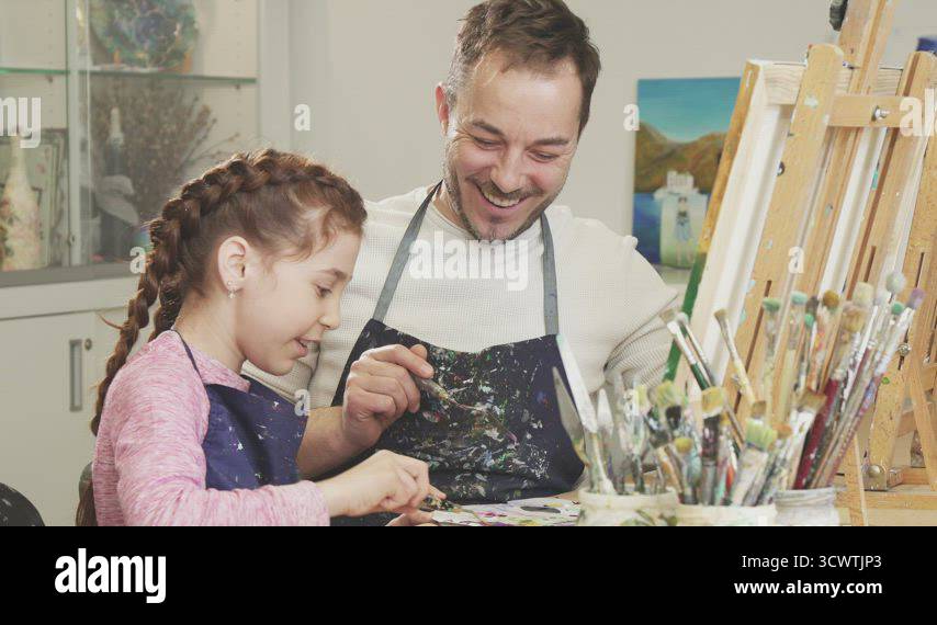 Father and daughter enjoying painting together high fiving at art ...