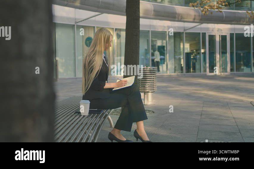 Successful young woman taking notes outdoors. Side view of elegant ...