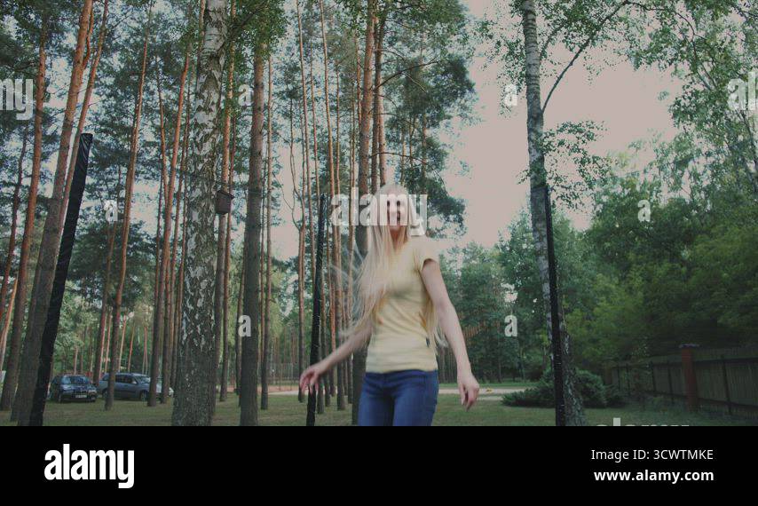 Happy female jumping on trampoline. Beautiful young blond barefoot ...