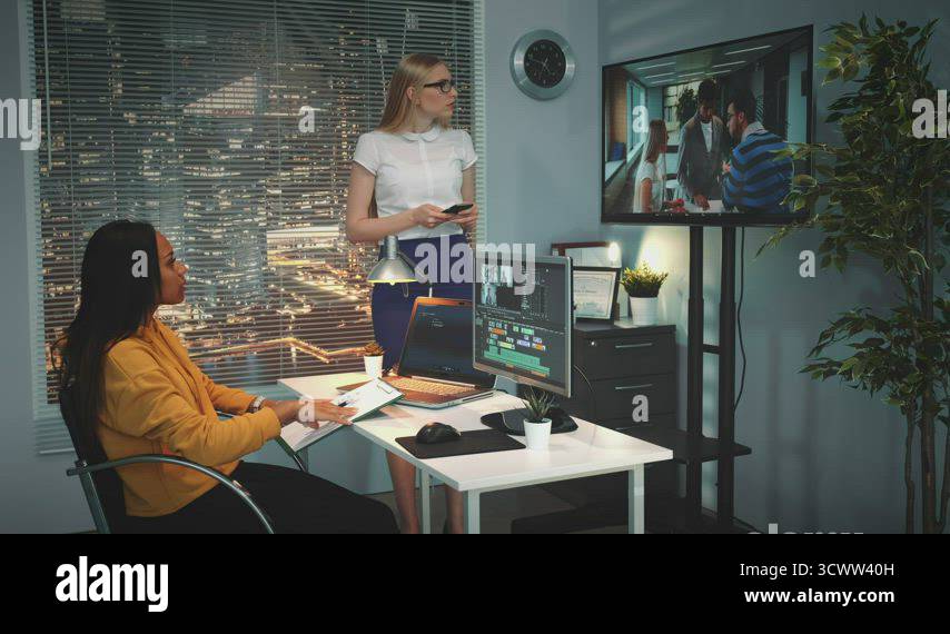 Professional video editor analyzing video project with colleague in ...