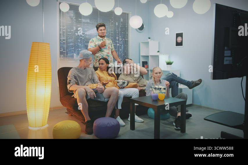 Young people watching TV and eating snacks together at home Stock Video ...