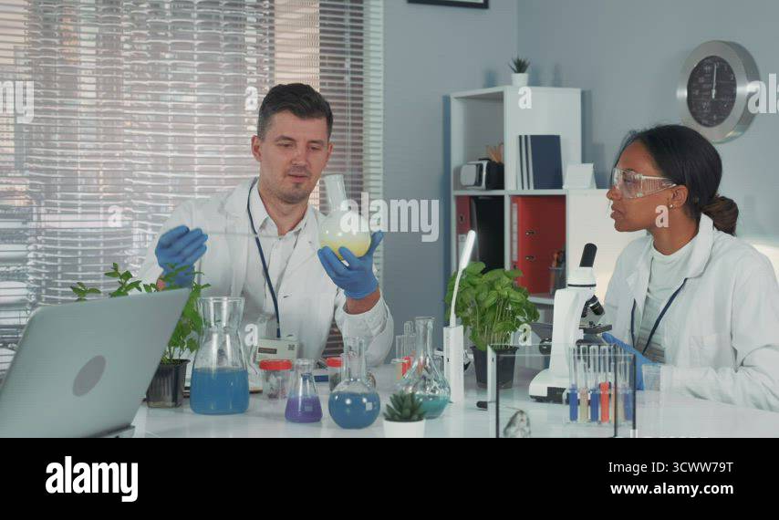Research scientist providing experiment with liquid in flask while his ...