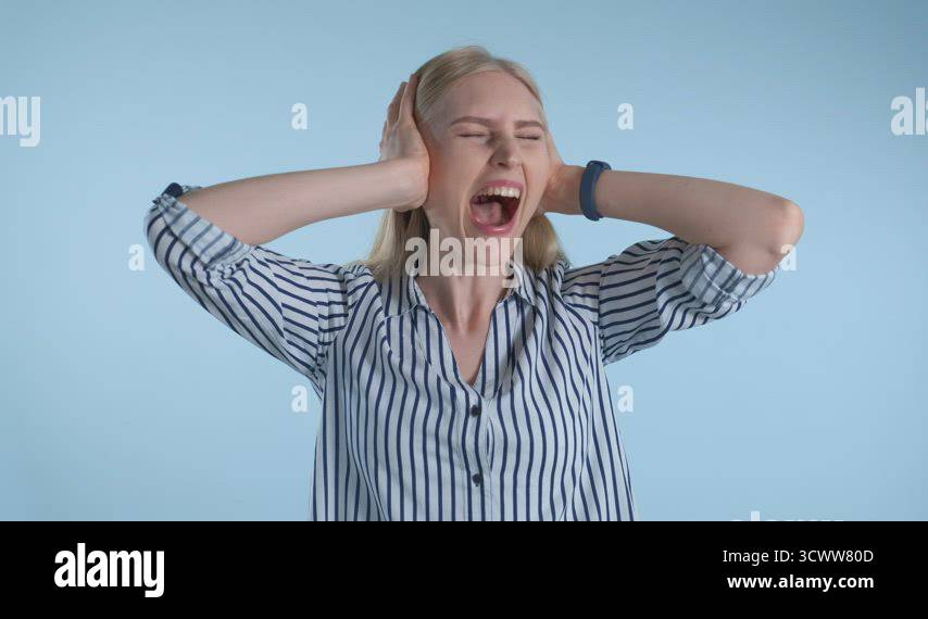 Scared desperate woman screaming and covering ears on blue background ...