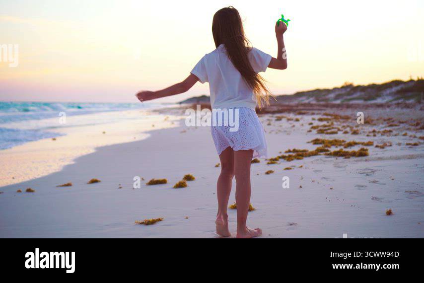 Little running girl with flying kite on tropical beach at sunset. Kids ...