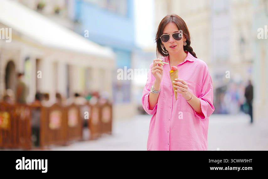 Young female model eating ice cream cone outdoors. Summer concept ...