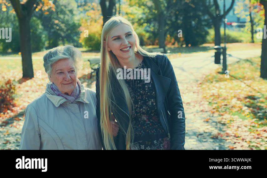 Old woman and pretty young woman hugging each other while walking ...