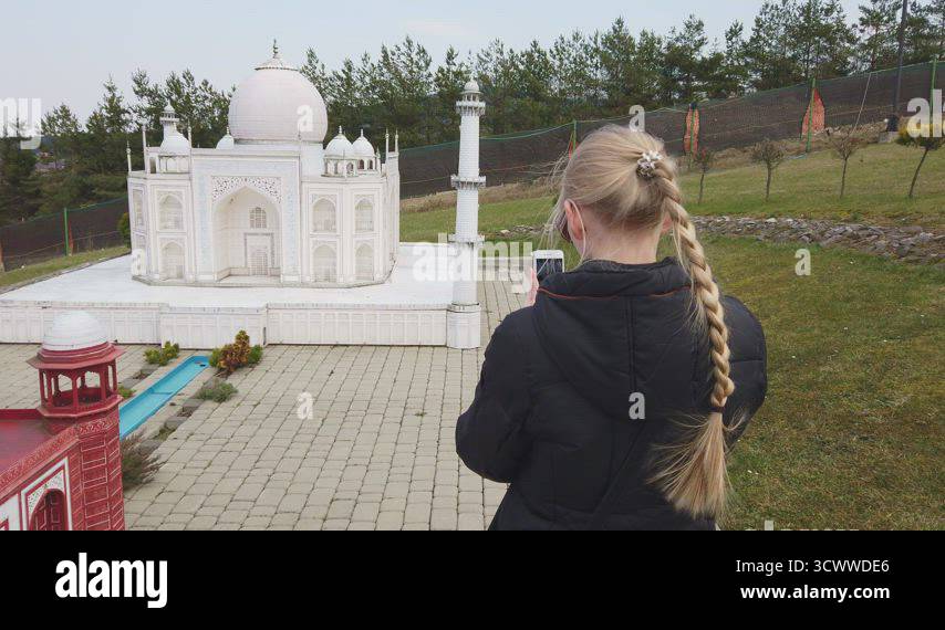Woman makes photo walking on foot near a miniature model of the Taj ...