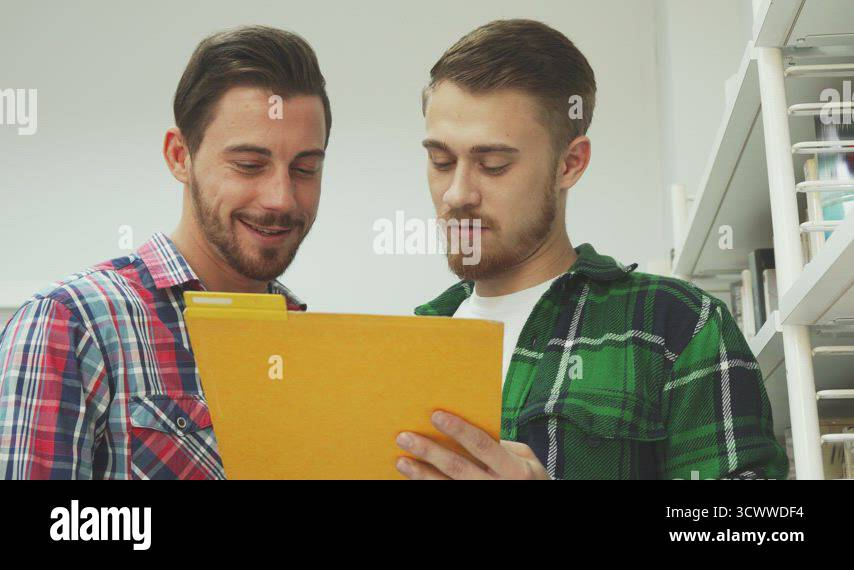 Two guys read papers in a folder and laugh Stock Video Footage - Alamy