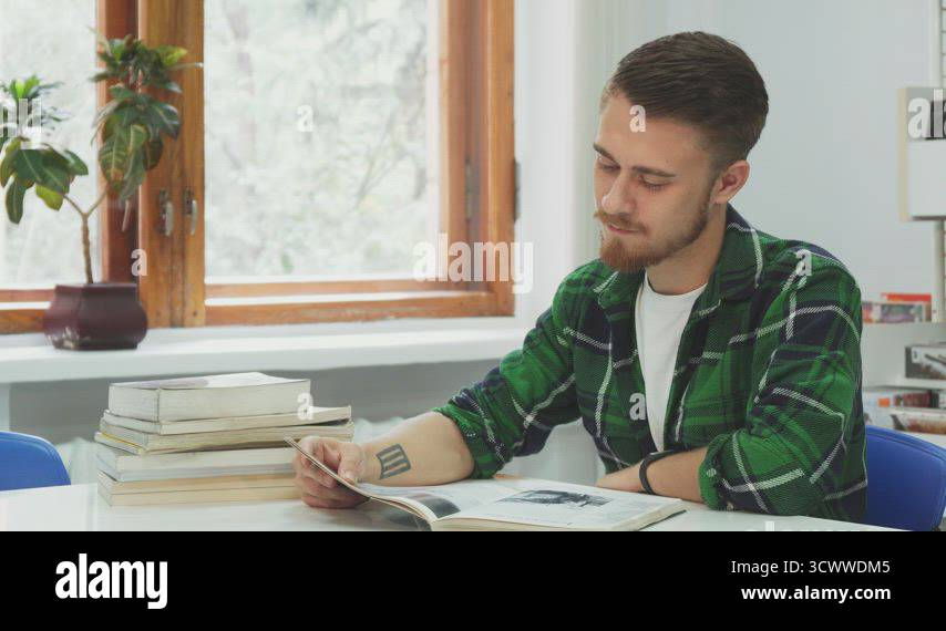 A cute guy laughs at what he read in the book Stock Video Footage - Alamy