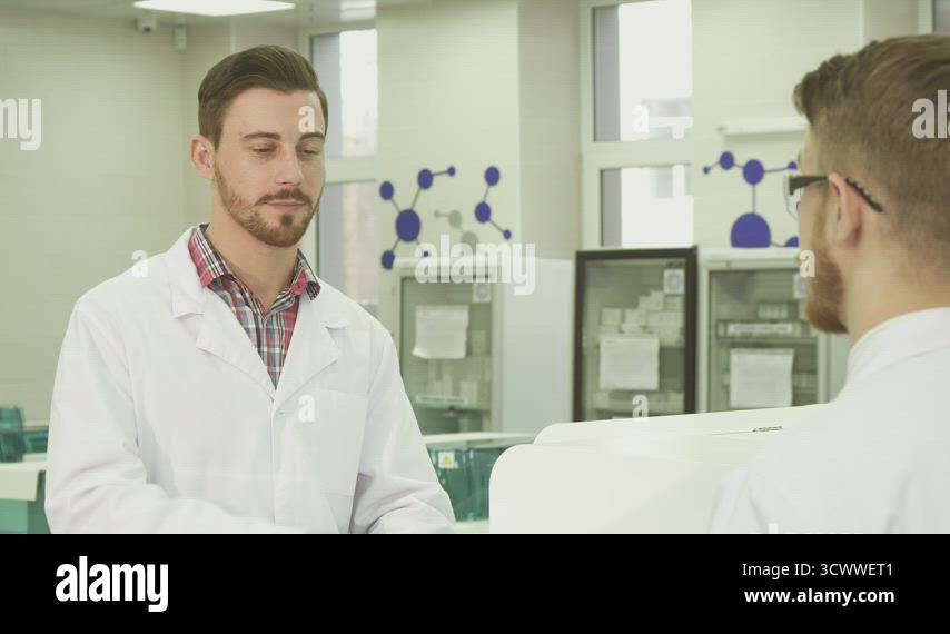 One lab technician hands over test tubes to his colleague for ...