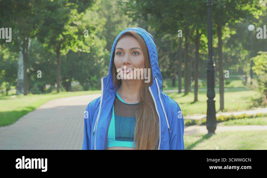 Attractive sportswoman taking off the hood before running in the park ...