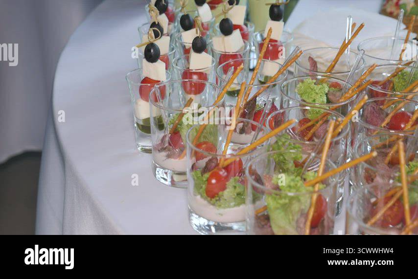 The waiter puts a tray with canapes on the table with snacks on the ...