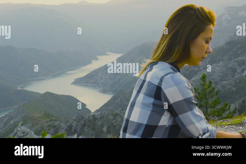 beautiful girl enjoying the view of a river lake and taking selfy ...