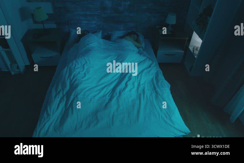 Top view of young woman waking up after a bad dream turning the lamp on ...