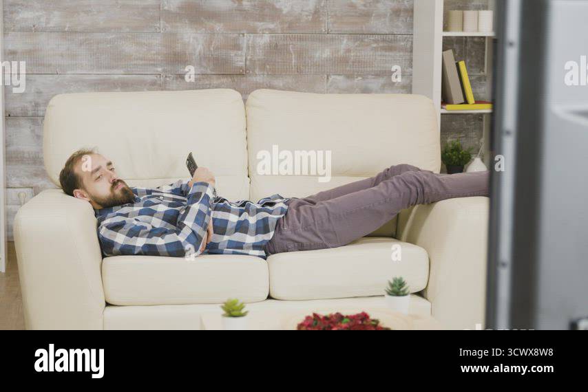 Unhappy man watching tv laid down on sofa Stock Video Footage - Alamy