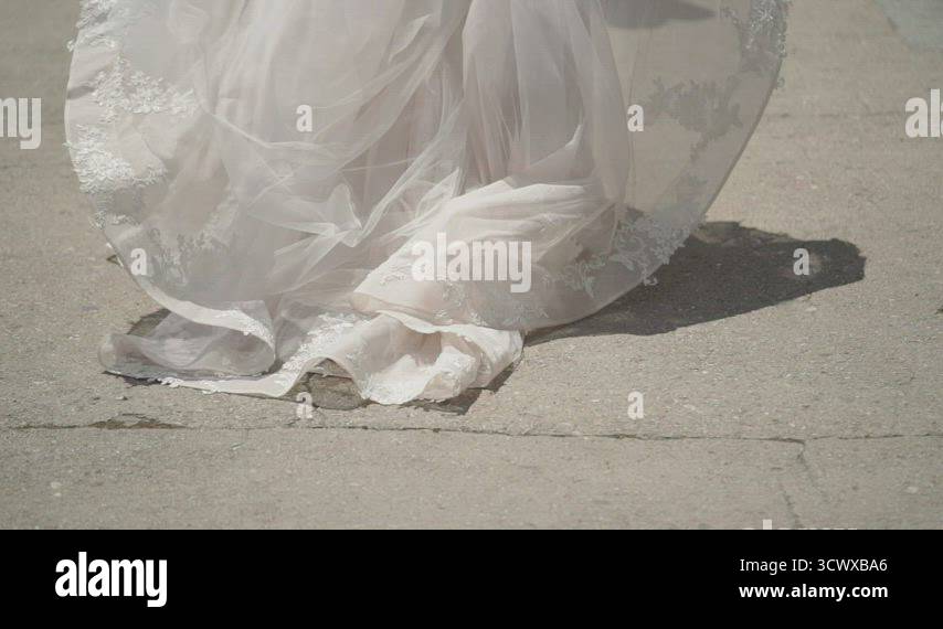 Young bride and groom posing in a city. Waving veil at windy summer day ...