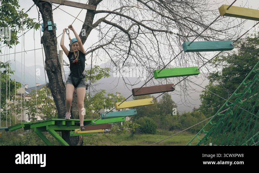 Happy school girl enjoying activity in a climbing adventure park on a ...