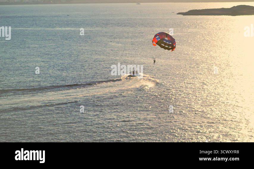 Speedboat towing a person under a parachute Stock Video Footage - Alamy