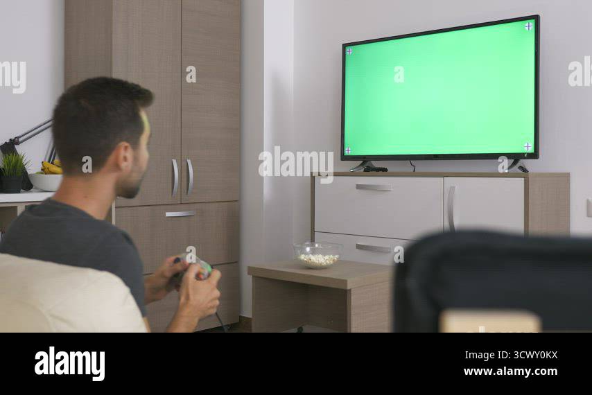 Man playing a video game on the console in front of green mock-up ...