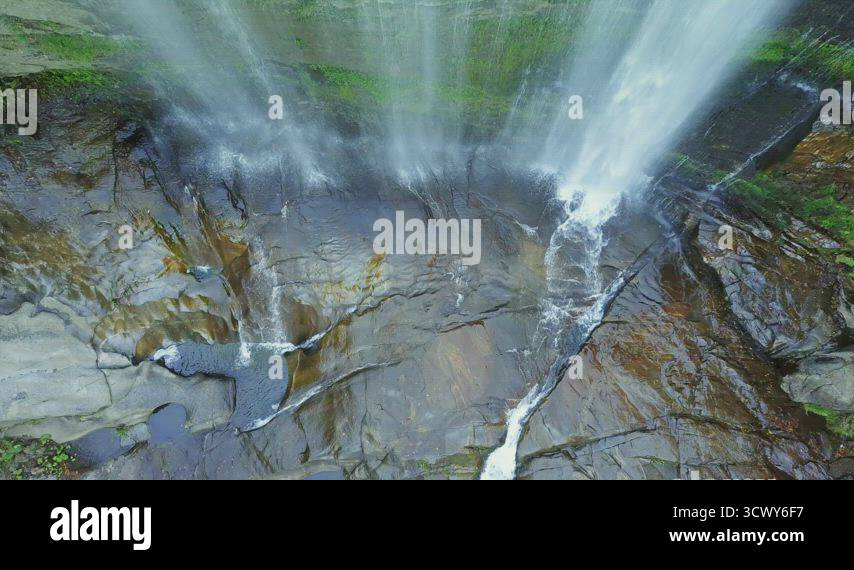 Upside down, Aerial shot. Flowing water of waterfall in mossy rocks at ...