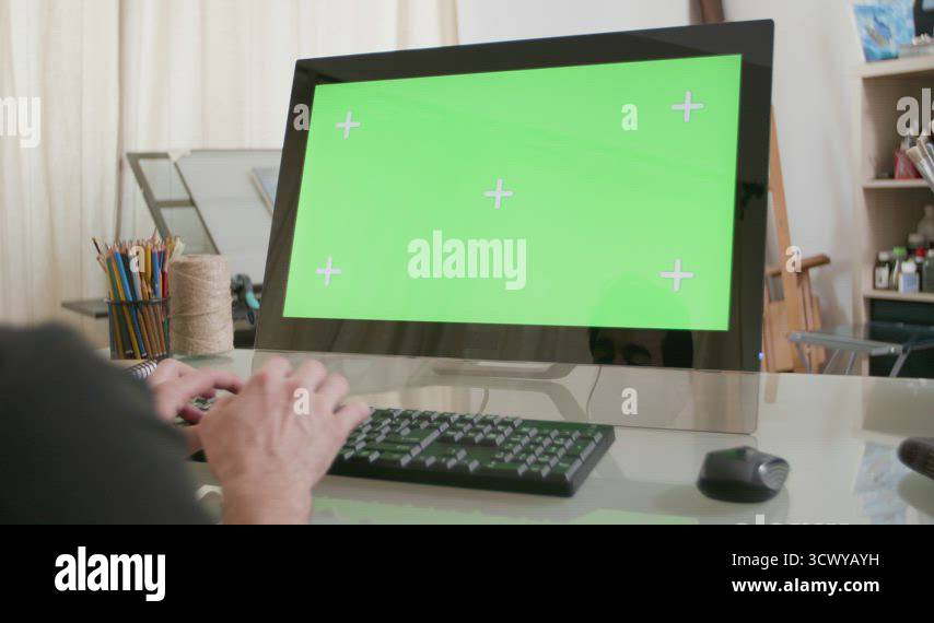 Man typing a text on his keyboard with a green screen on his monitor ...