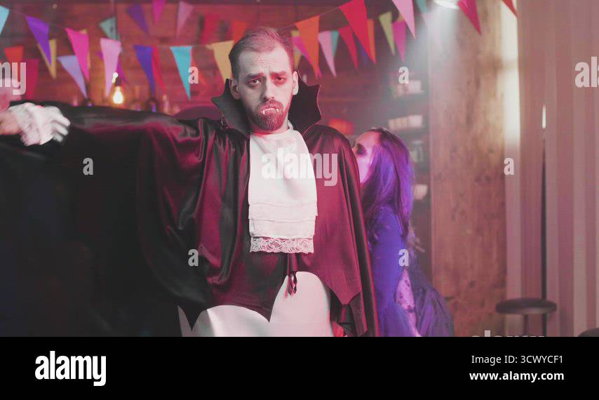 Man in vampire costume hides behing the cloack at a halloween party ...