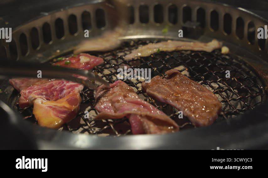 Close-up shoot grilled beef buffet. Hands are grilling meat, BBQ or ...