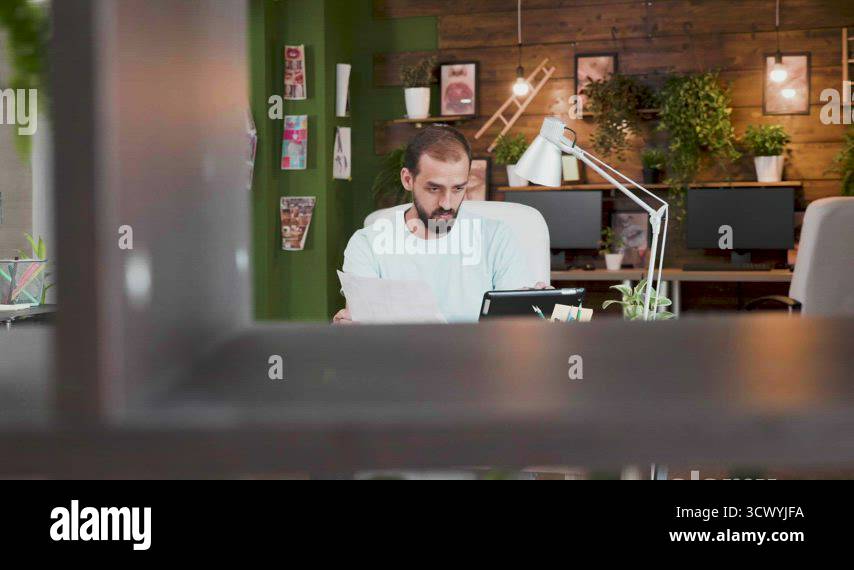 Creative young designer writing notes and working on his laptop at the ...