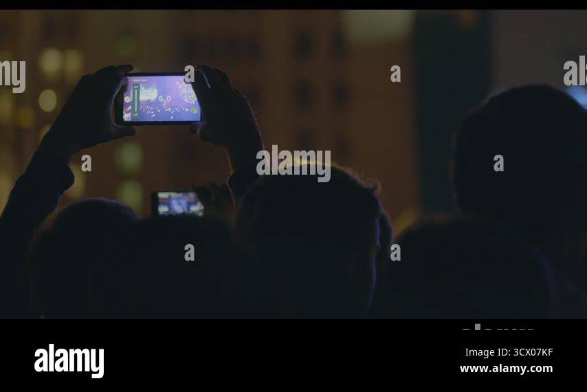 Spectator man recording video with zoom of stage and big screen via ...